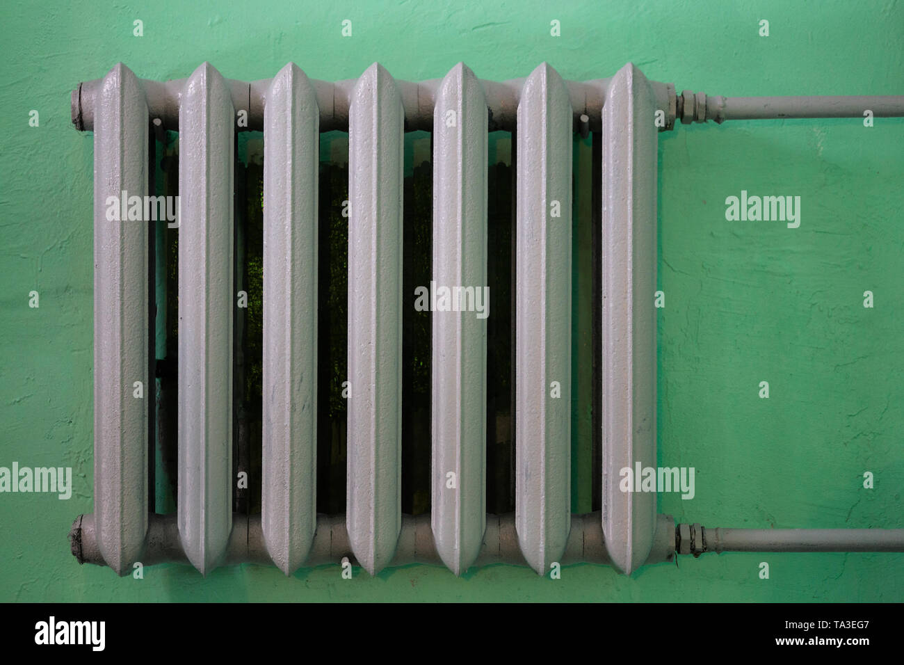 gray painted cast iron water radiator on green wall Stock Photo - Alamy