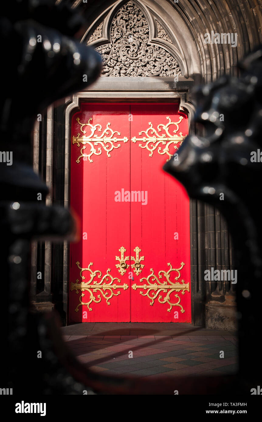 Traditional red wooden door with golden hinges seen through a stone ...