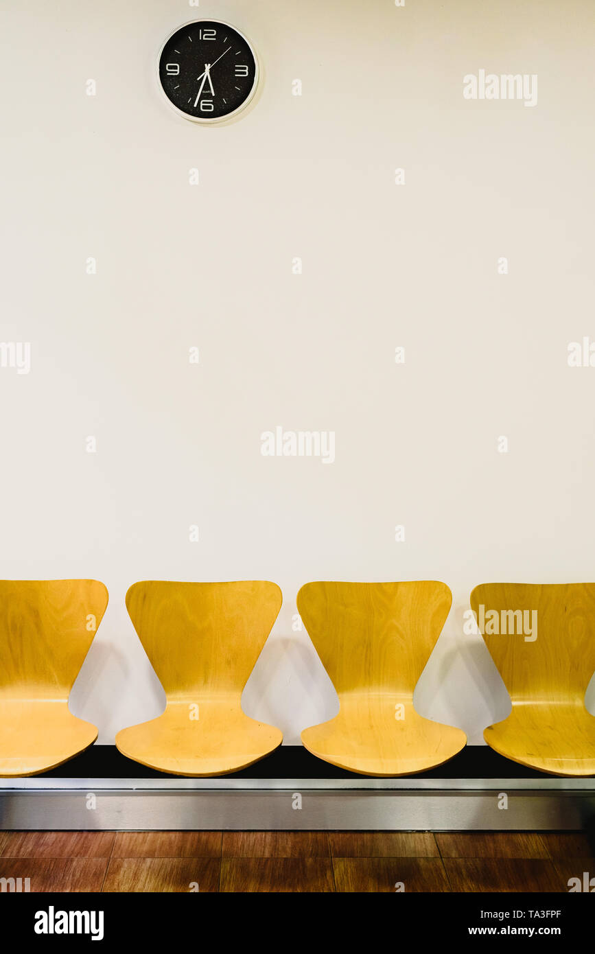 Waiting room with empty wooden chairs and wall clock, waiting concept ...