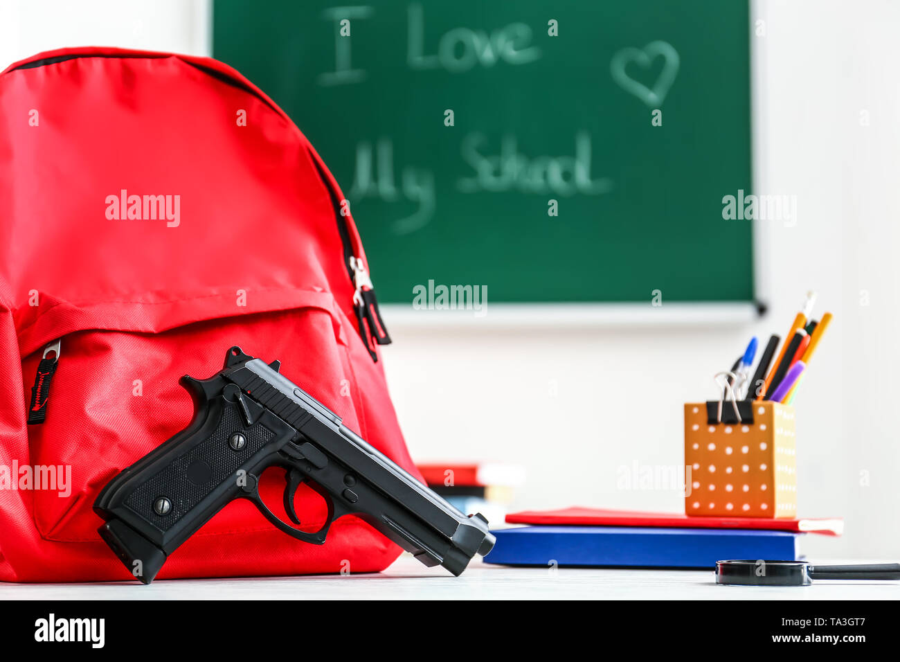 Backpack, pistol and stationery on table in classroom. No guns in ...