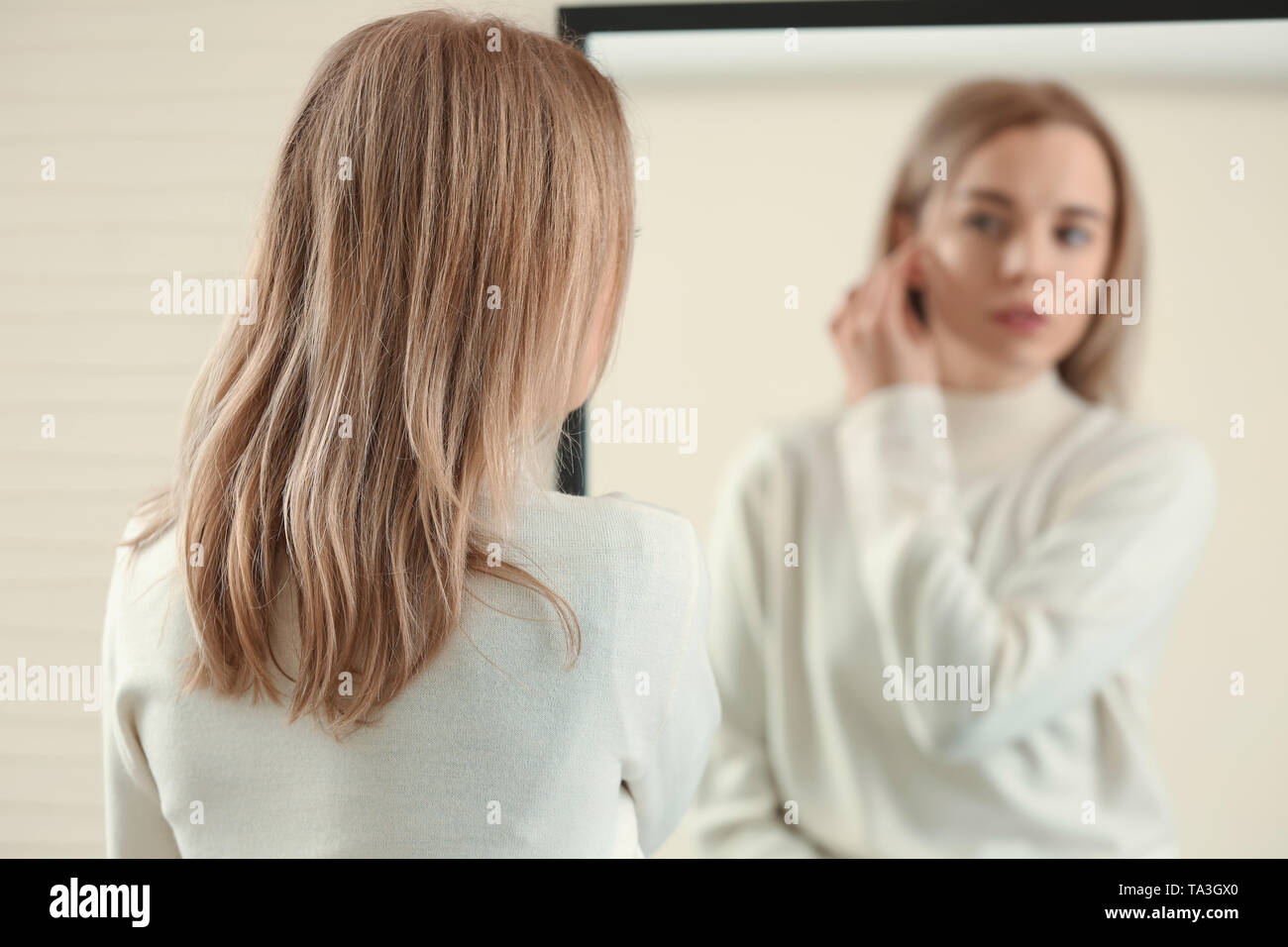 Beautiful young woman looking on her reflection in mirror Stock Photo ...