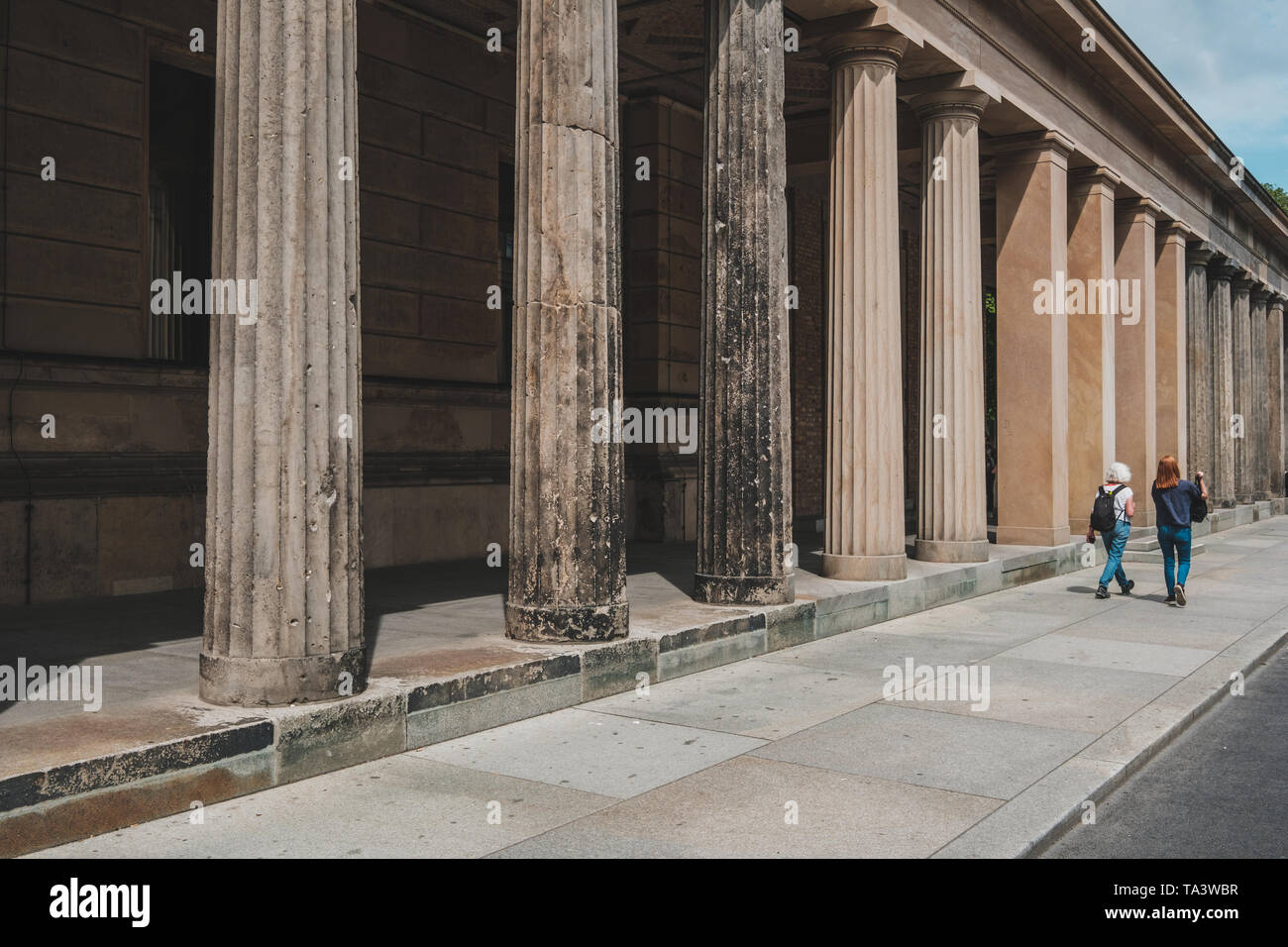 Two women walking by historic columns at the Museum Island in Berlin ...