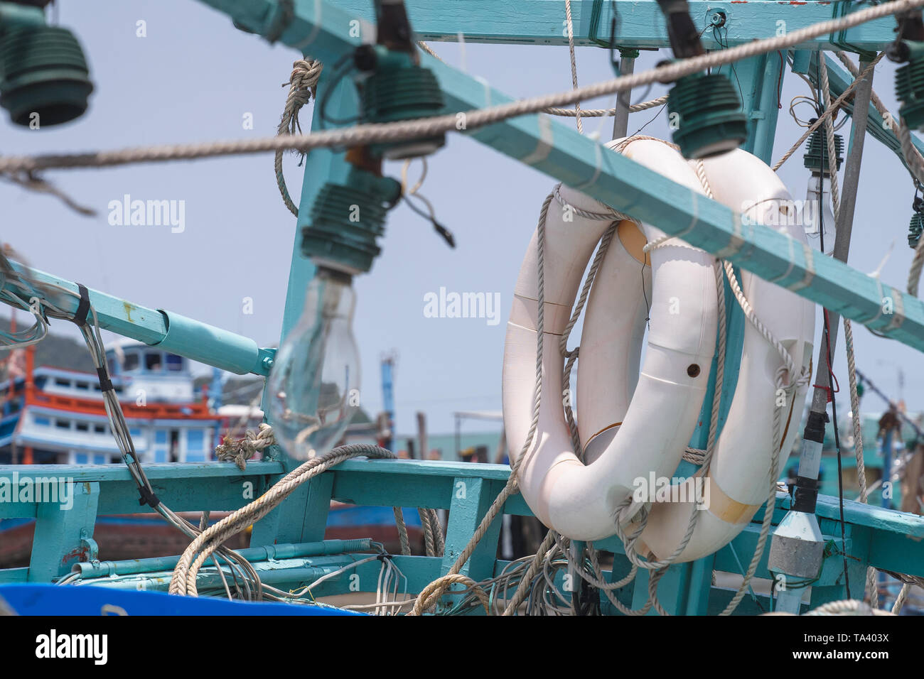 a white life ring hanged against green mint pole of wooden fishing boat ...