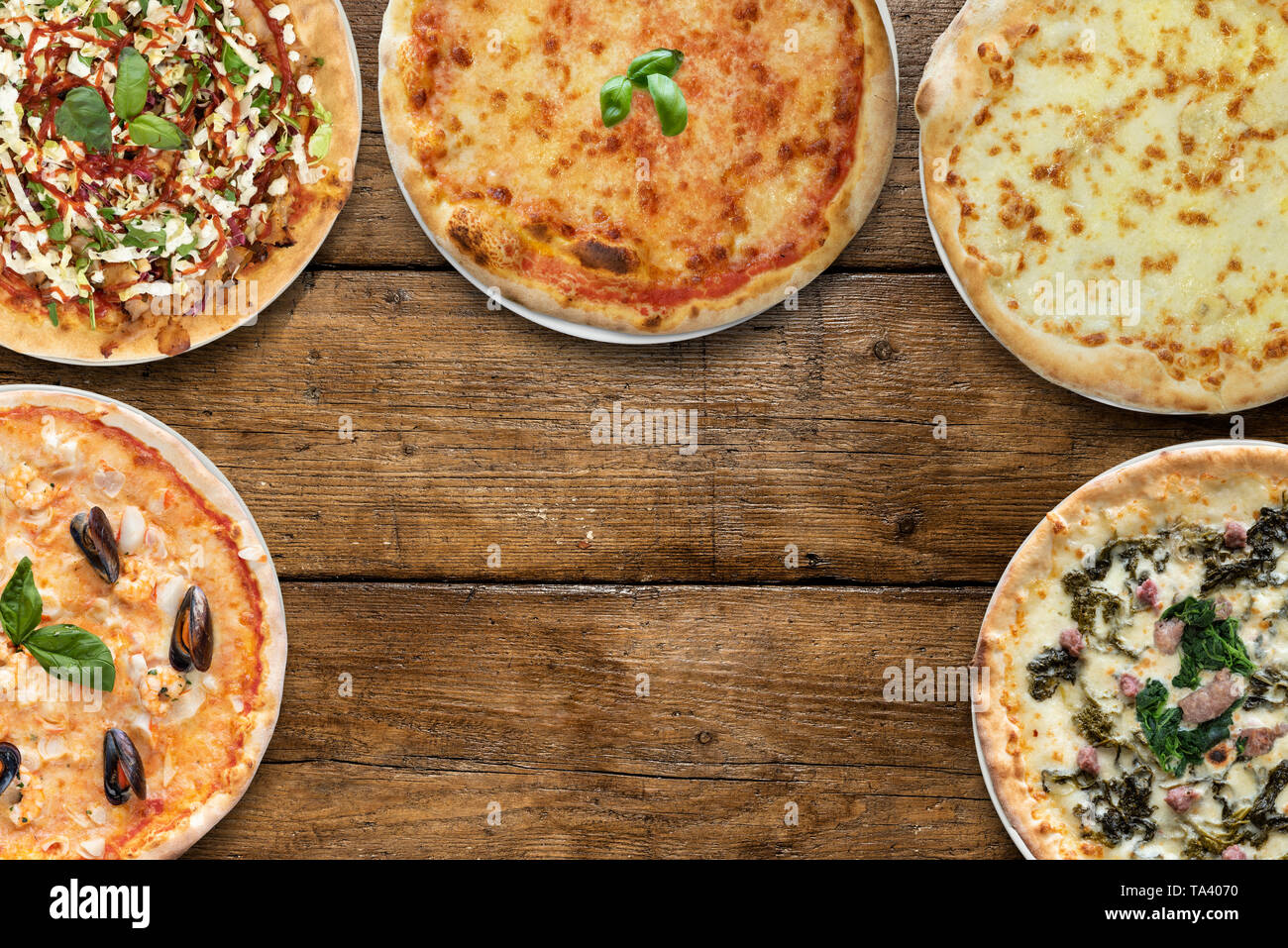 Variety of pizza on wooden table with copy space Stock Photo - Alamy