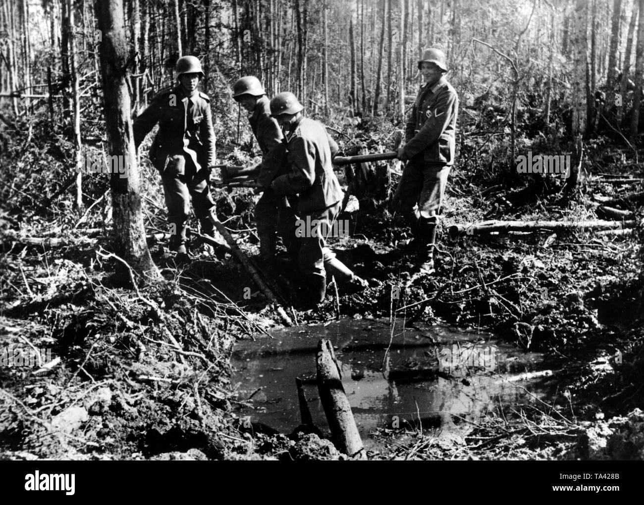 German soldiers carry the gun barrel of an anti-tank cannon through a ...