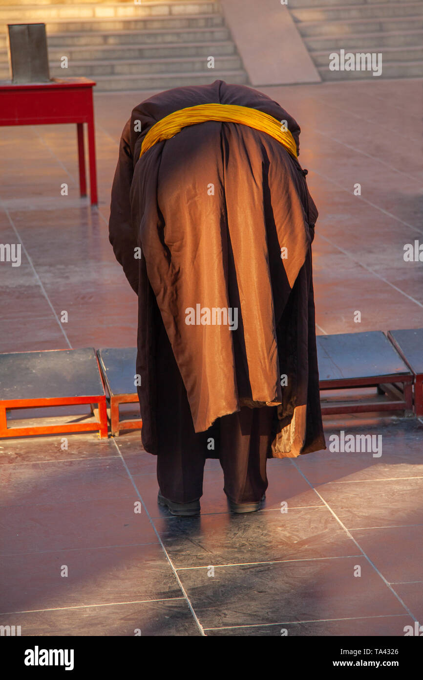 Monk bow down while praying in a buddhist temple yard in Beijing, China ...