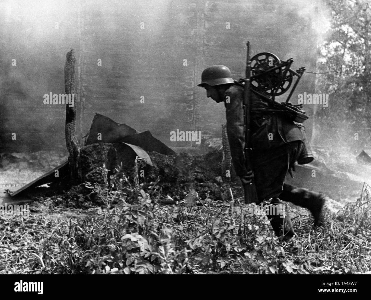 A German soldier lays a telephone cable, which connects the units on ...