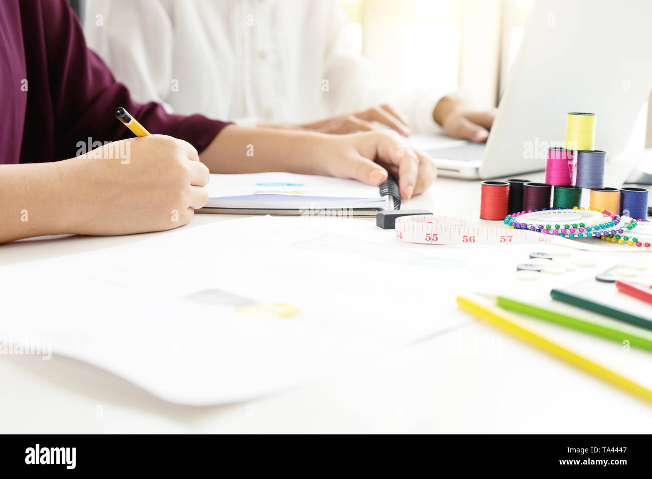professional Fashion designer working and drawing sketches on the table ...