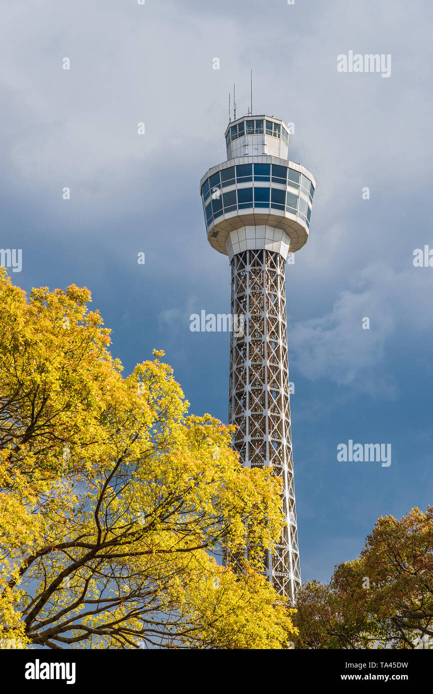 Yokohama Maritime Tower rises in the clouds and above trees. Completed ...