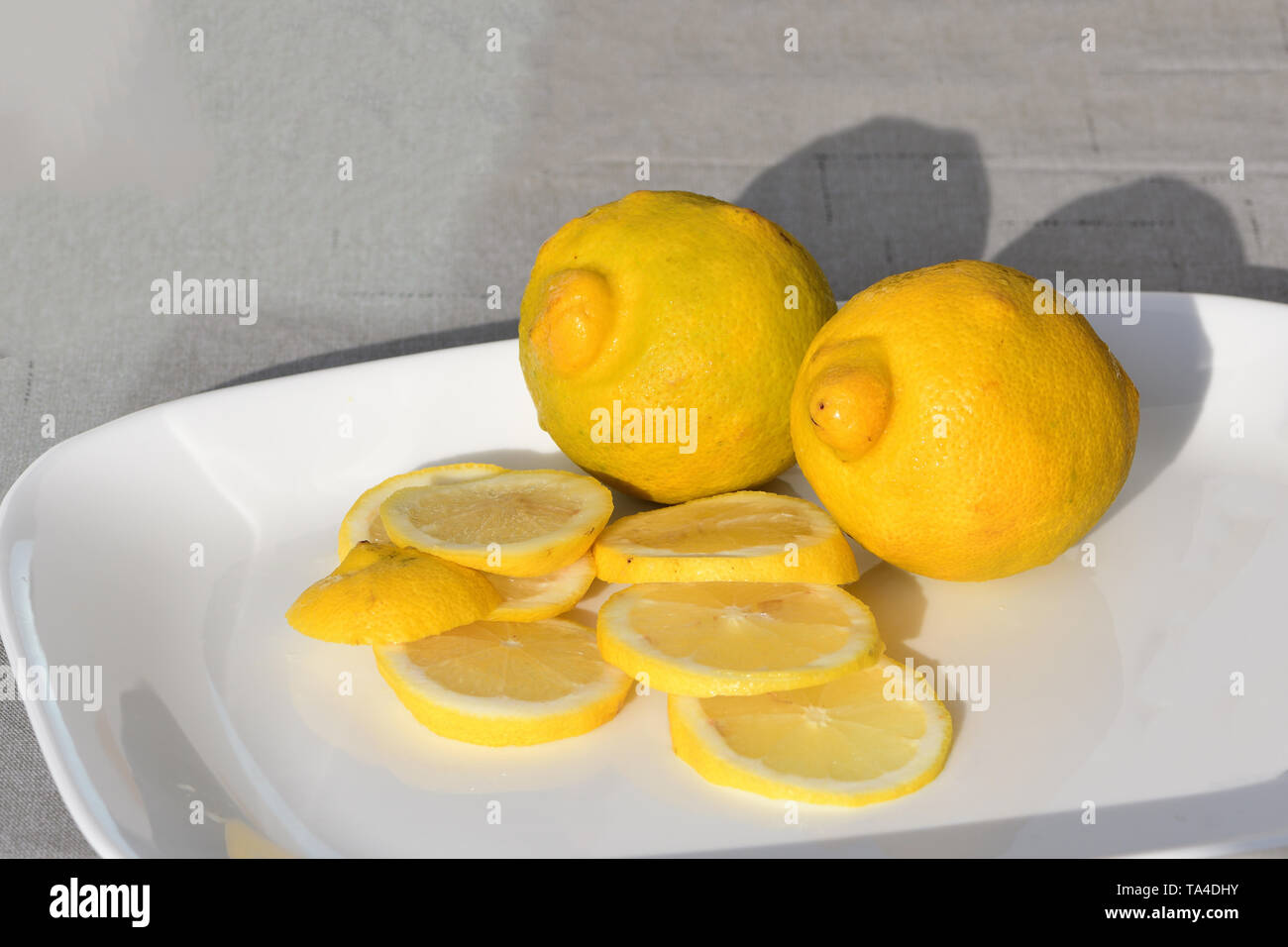 Whole and sliced lemons on white platter Stock Photo - Alamy