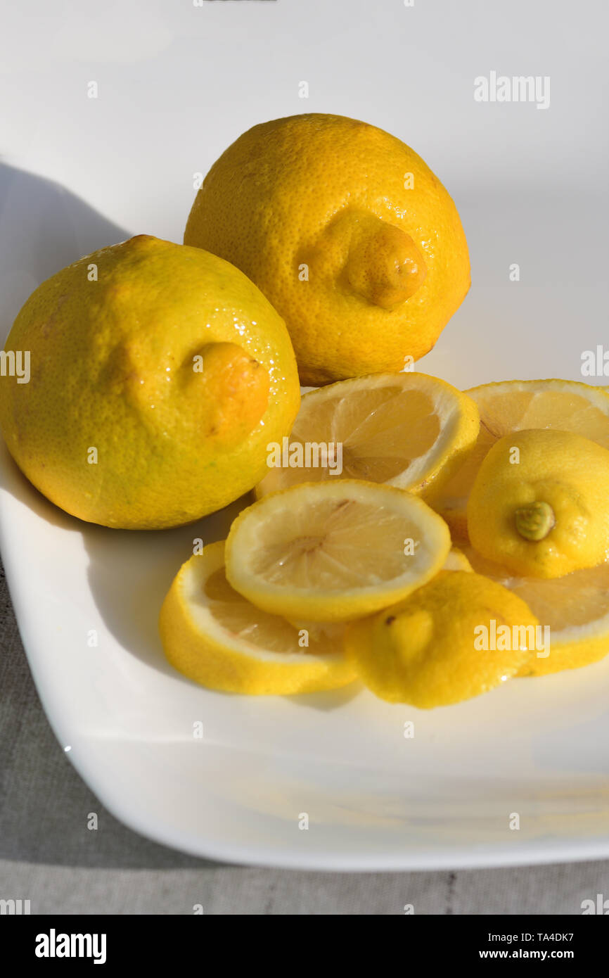 Whole and sliced lemons on white platter Stock Photo - Alamy