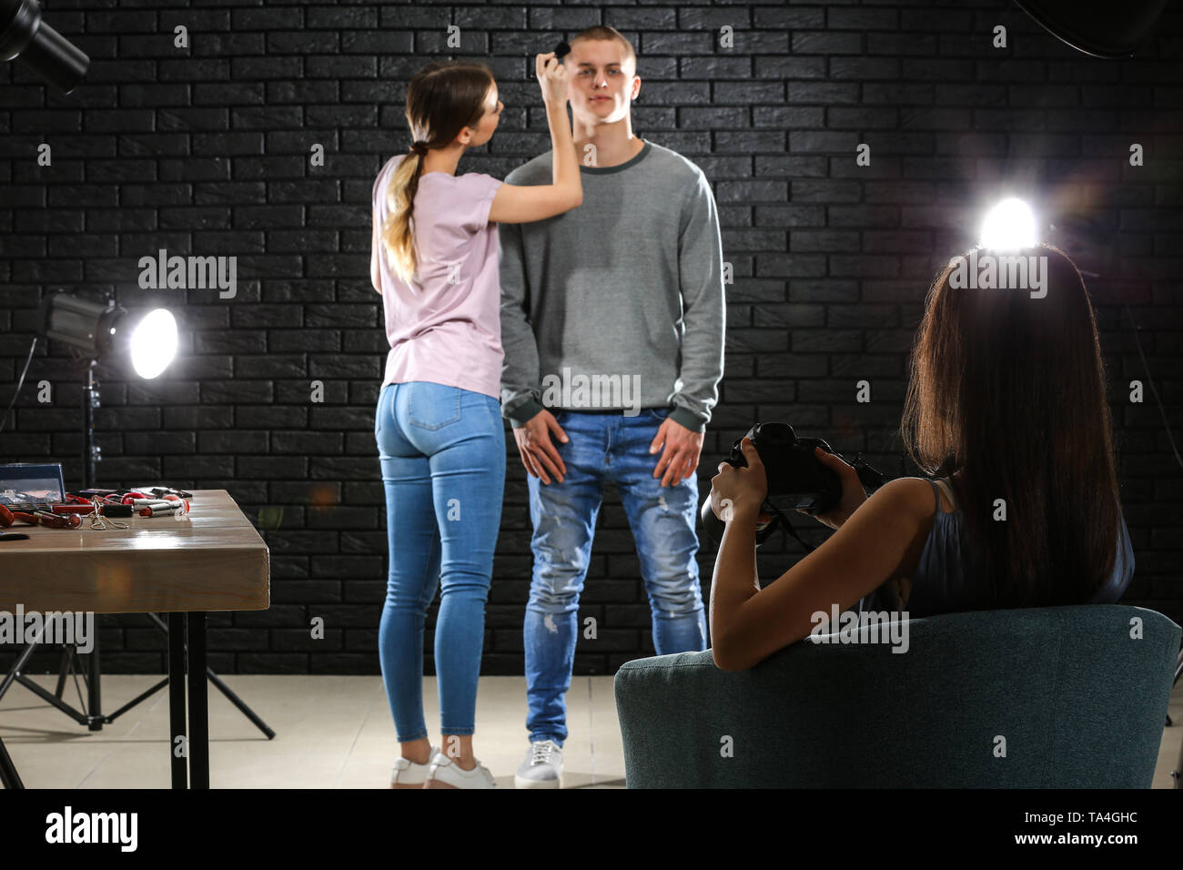 Professional makeup artist working with young model in photo studio ...