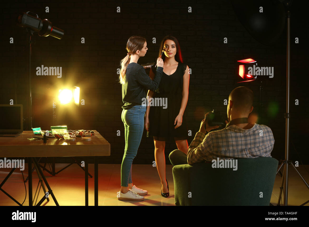 Professional makeup artist working with young model in photo studio ...