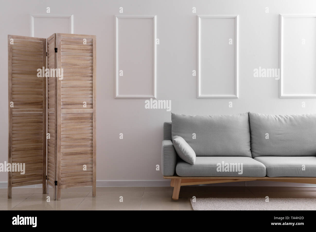 Interior of room with comfortable sofa and folding screen Stock Photo ...