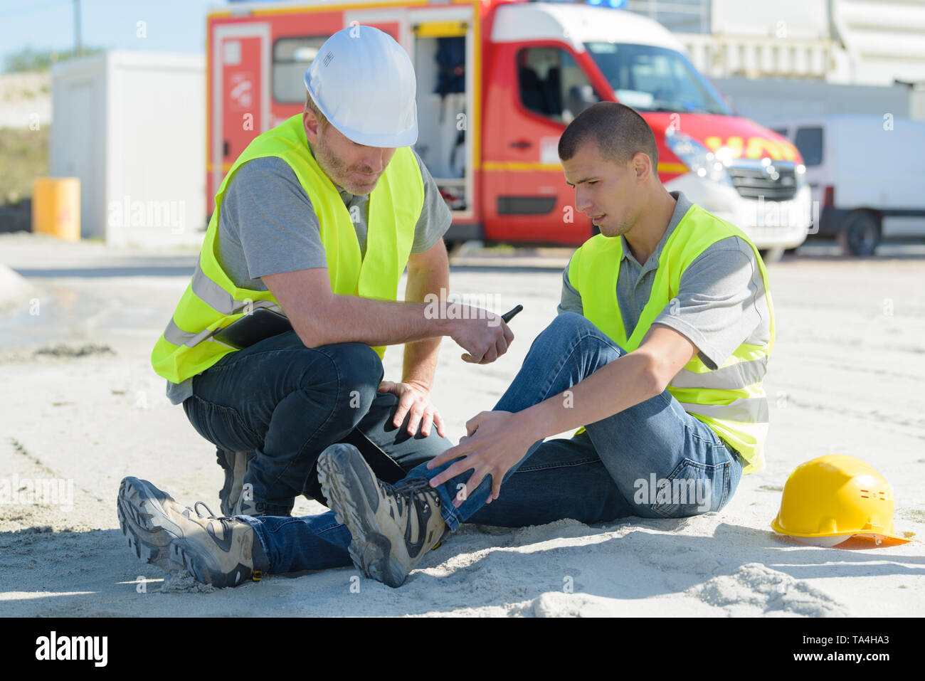 young construction worker on site with injured ankle Stock Photo - Alamy