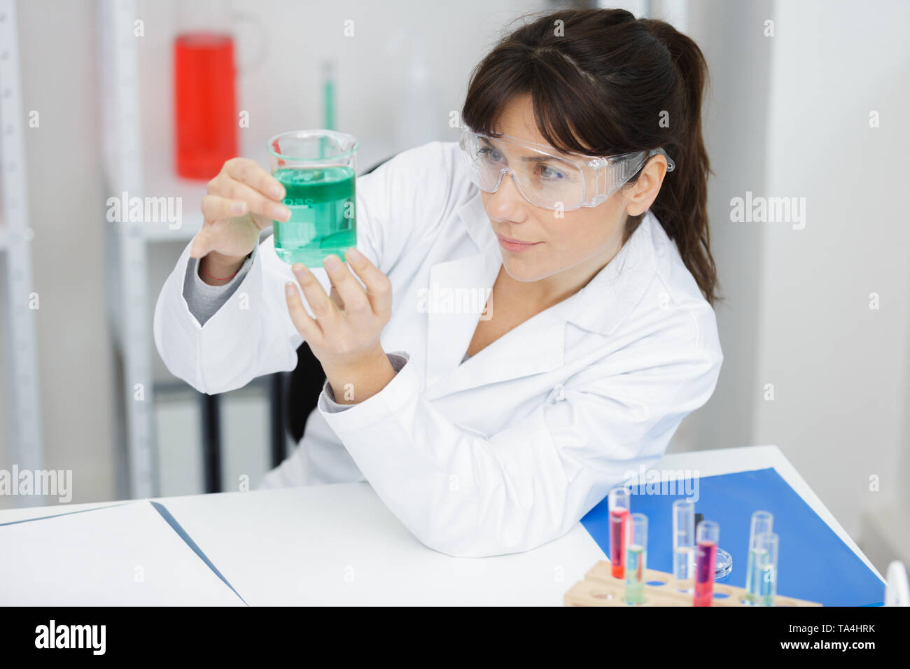 female worker mixing blue liquid in a beaker Stock Photo - Alamy