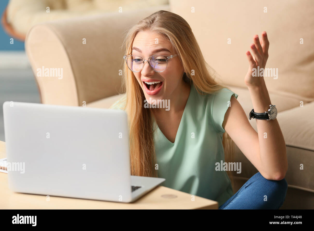 Emotional young woman using laptop at home Stock Photo - Alamy
