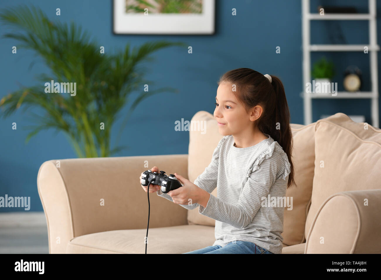 Cute little girl playing computer game at home Stock Photo - Alamy