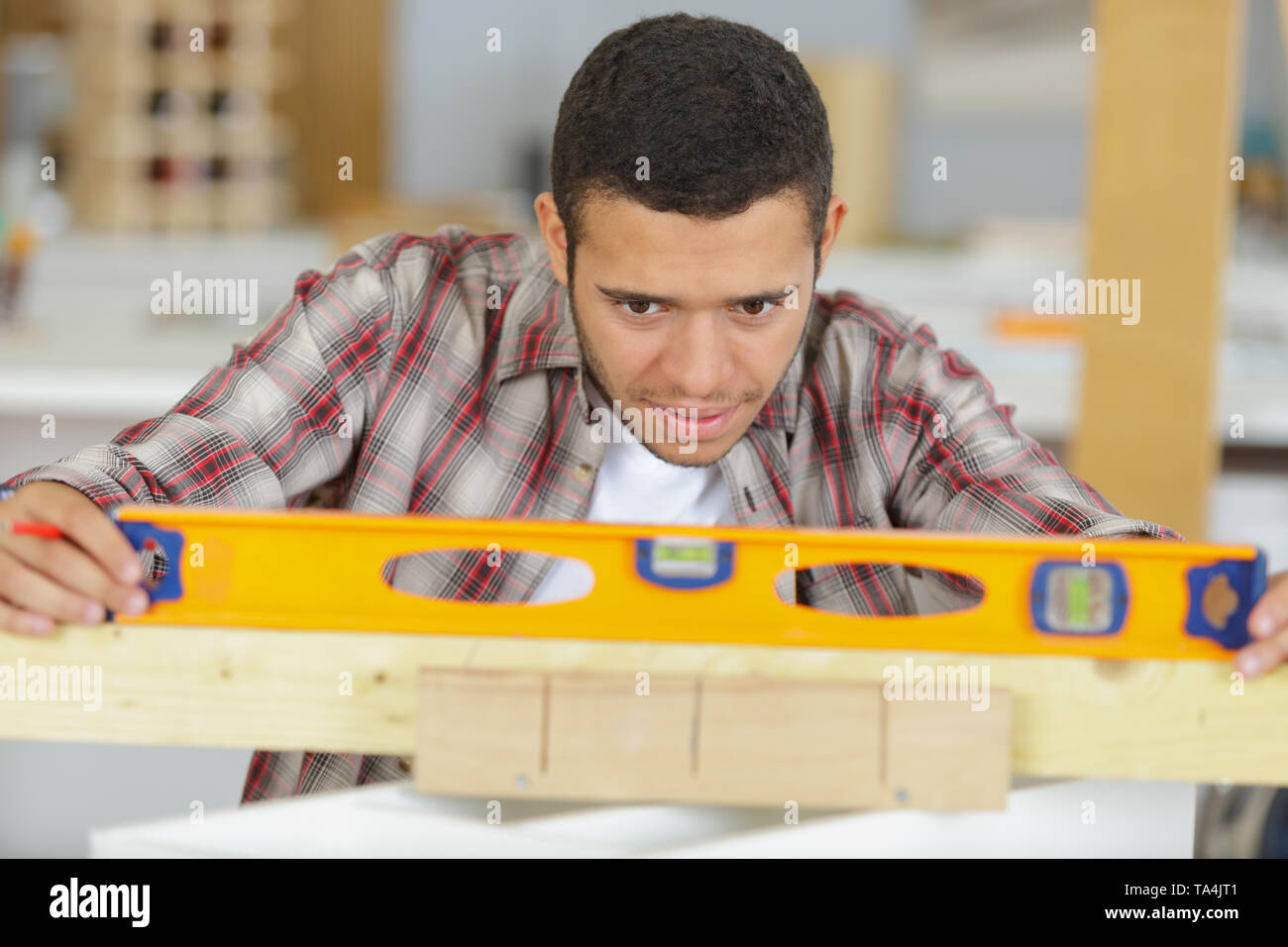 young man checking levelness of wood with spirit level Stock Photo - Alamy
