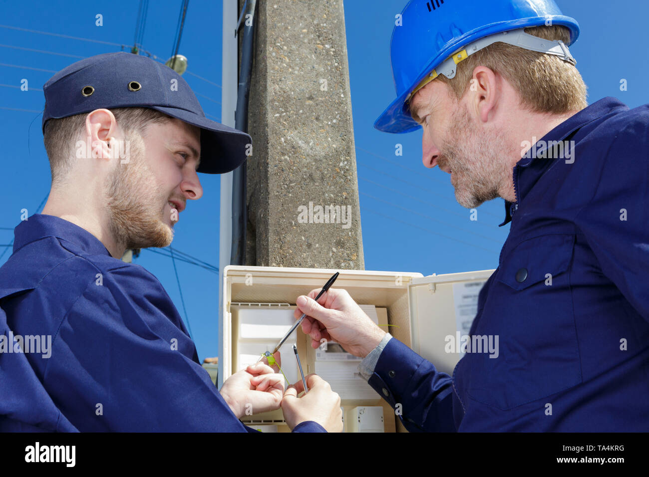 two male electricians looking at connection in outdoor meter Stock ...
