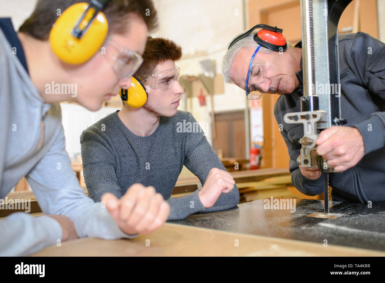 apprentices watching teacher set up bench saw Stock Photo - Alamy