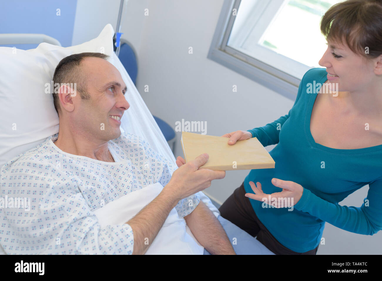 giving a book to ill patient in hospital Stock Photo - Alamy