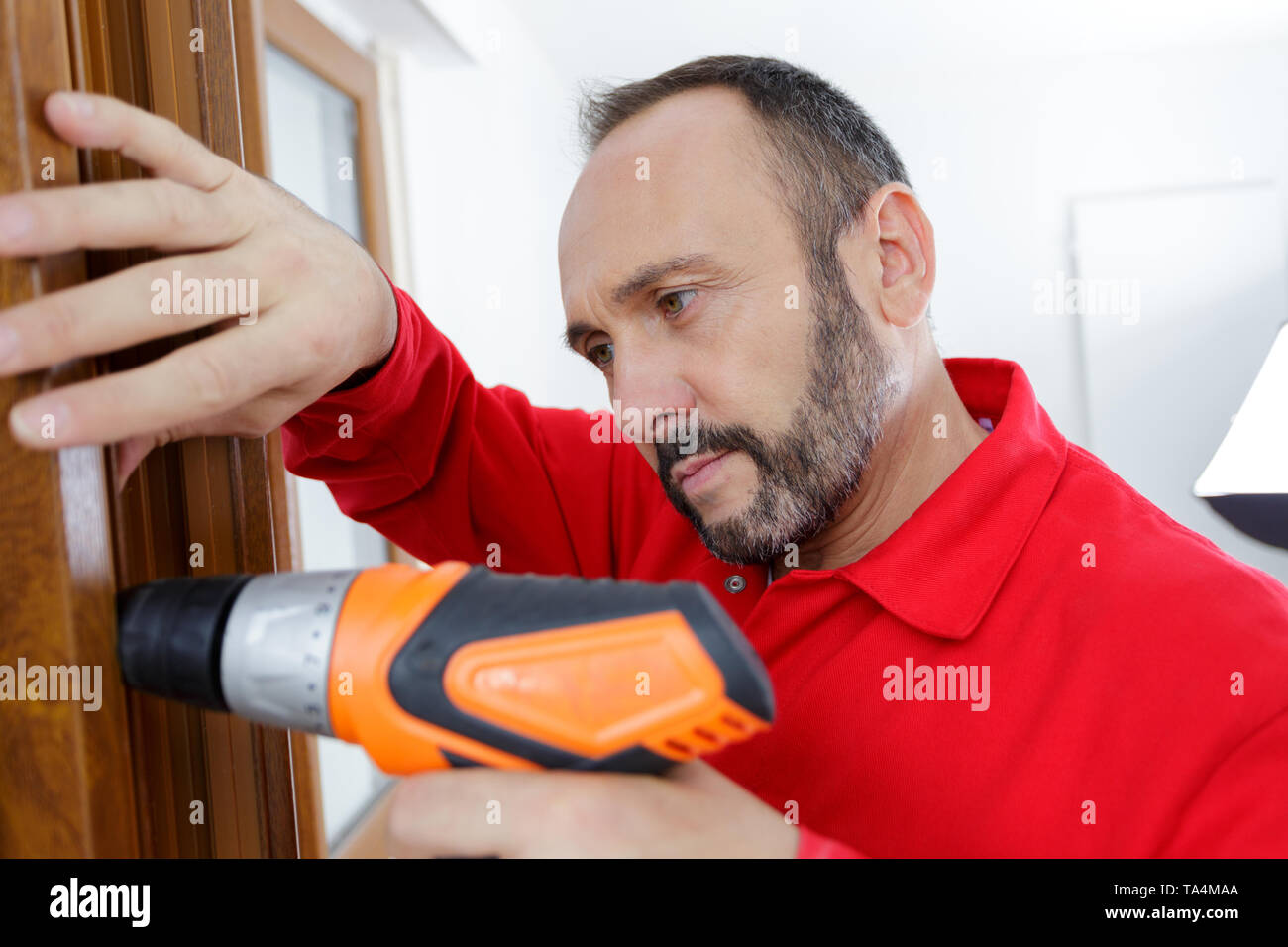 man drilling a hole in a window frame Stock Photo - Alamy