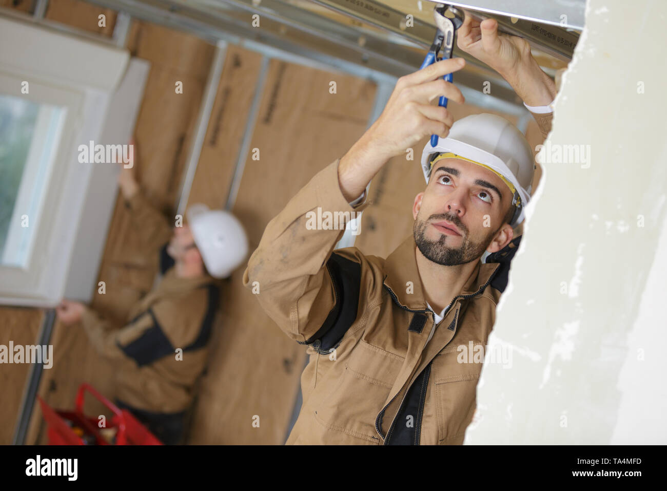 builder using tool to fix ceiling indoors Stock Photo - Alamy