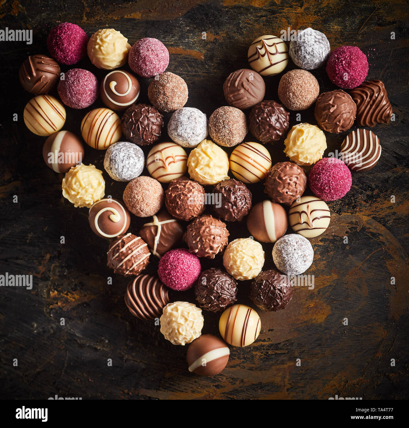 Gourmet handmade round assorted chocolates in a heart shape on a rustic ...