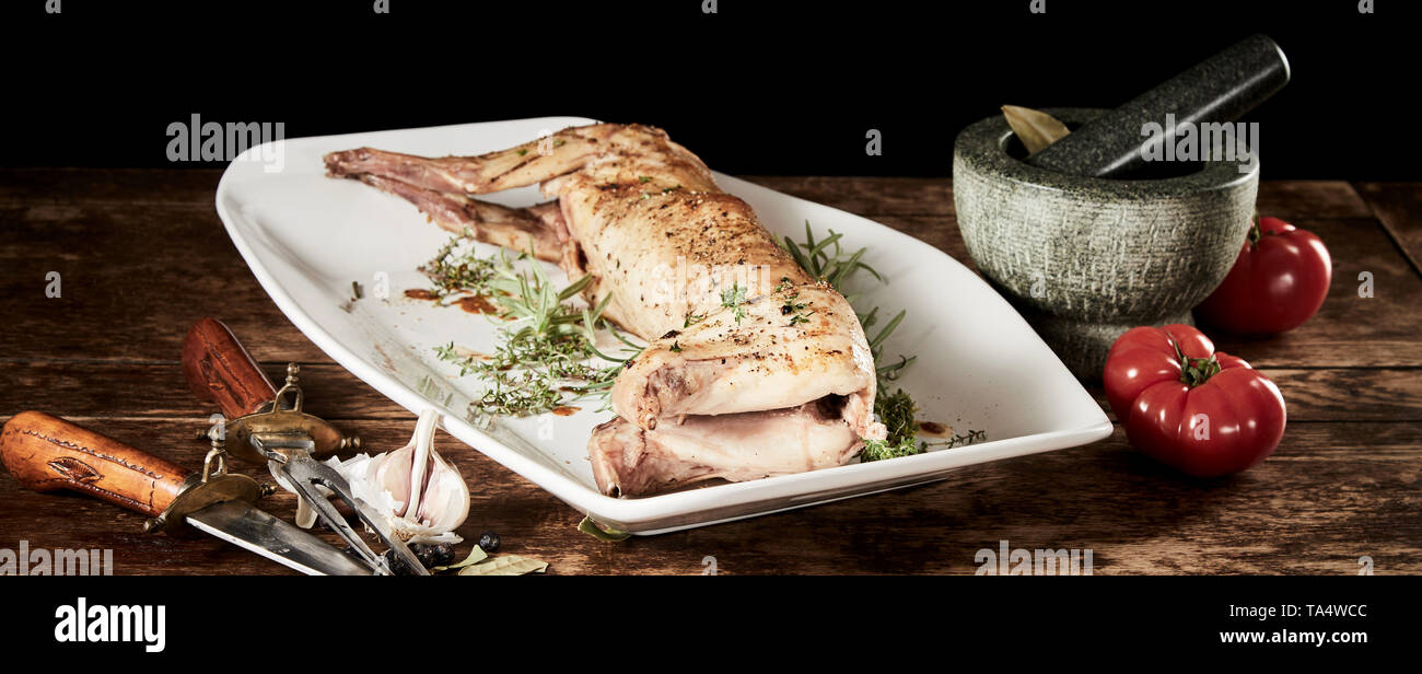 Roasted fresh wild rabbit venison served on a plate surrounded with ...