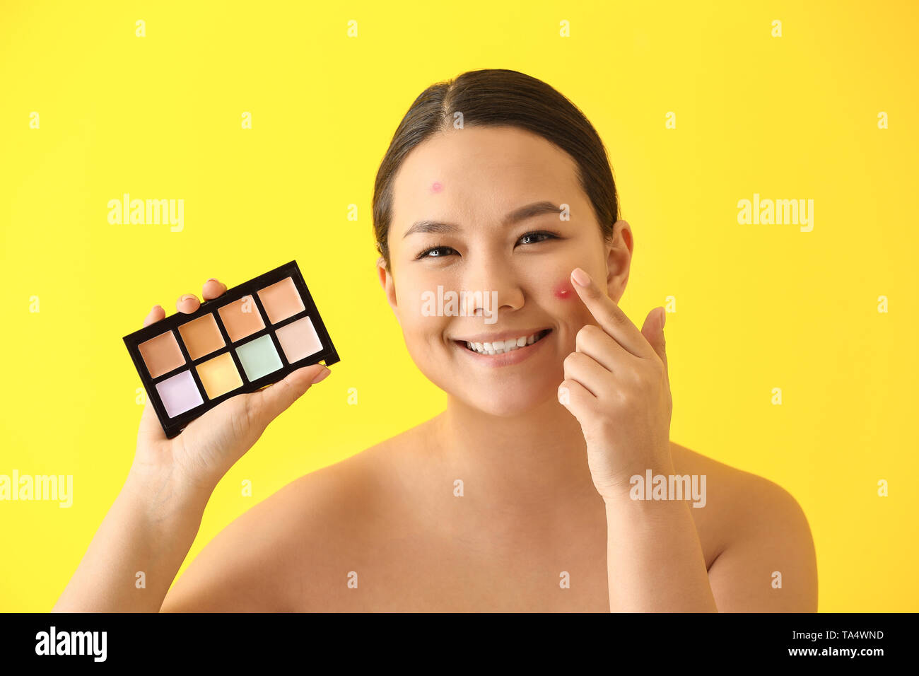 Portrait of young Asian woman with palette of concealers for masking ...