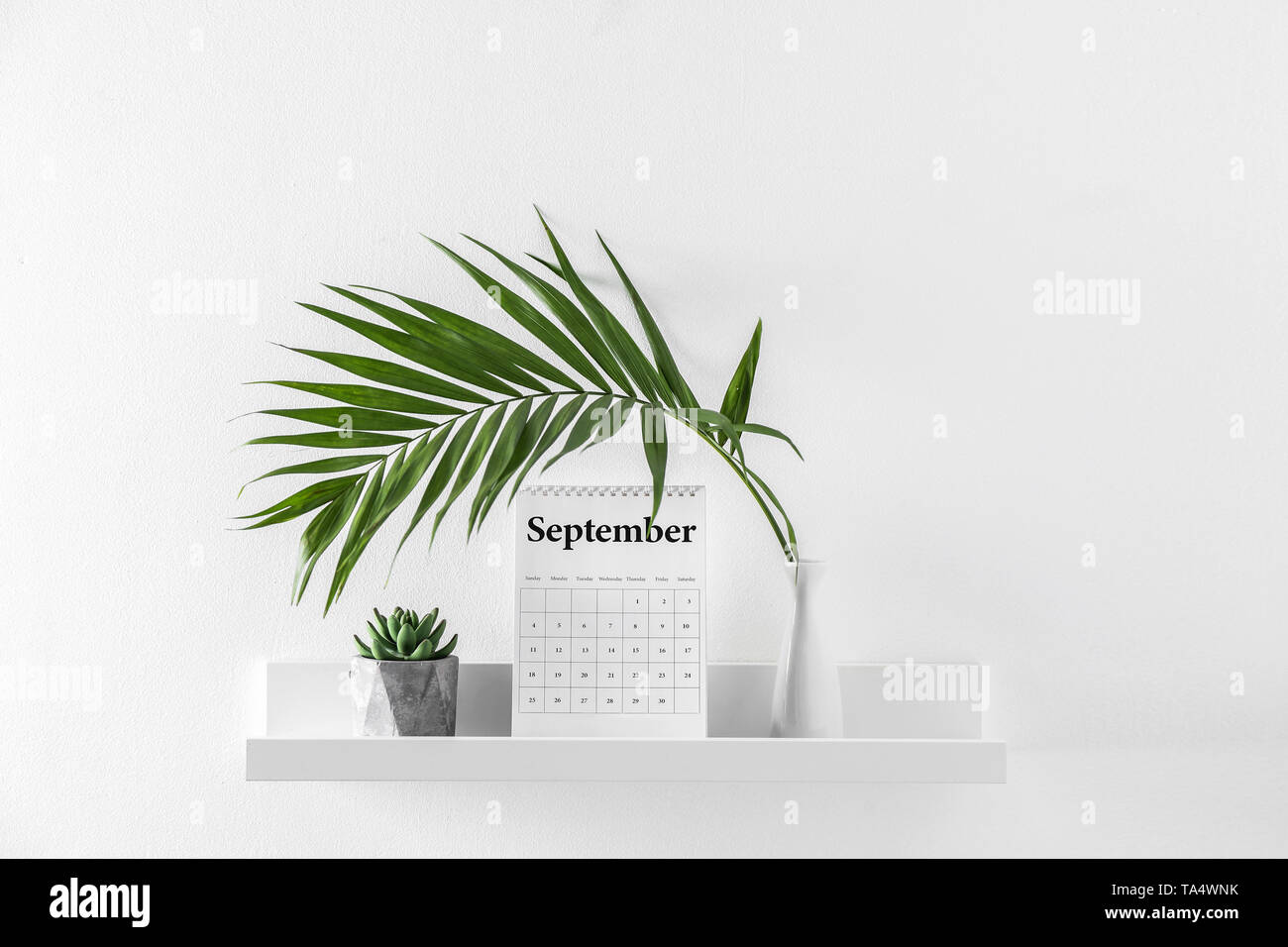 Flip calendar and vase with tropical leaf on shelf Stock Photo - Alamy