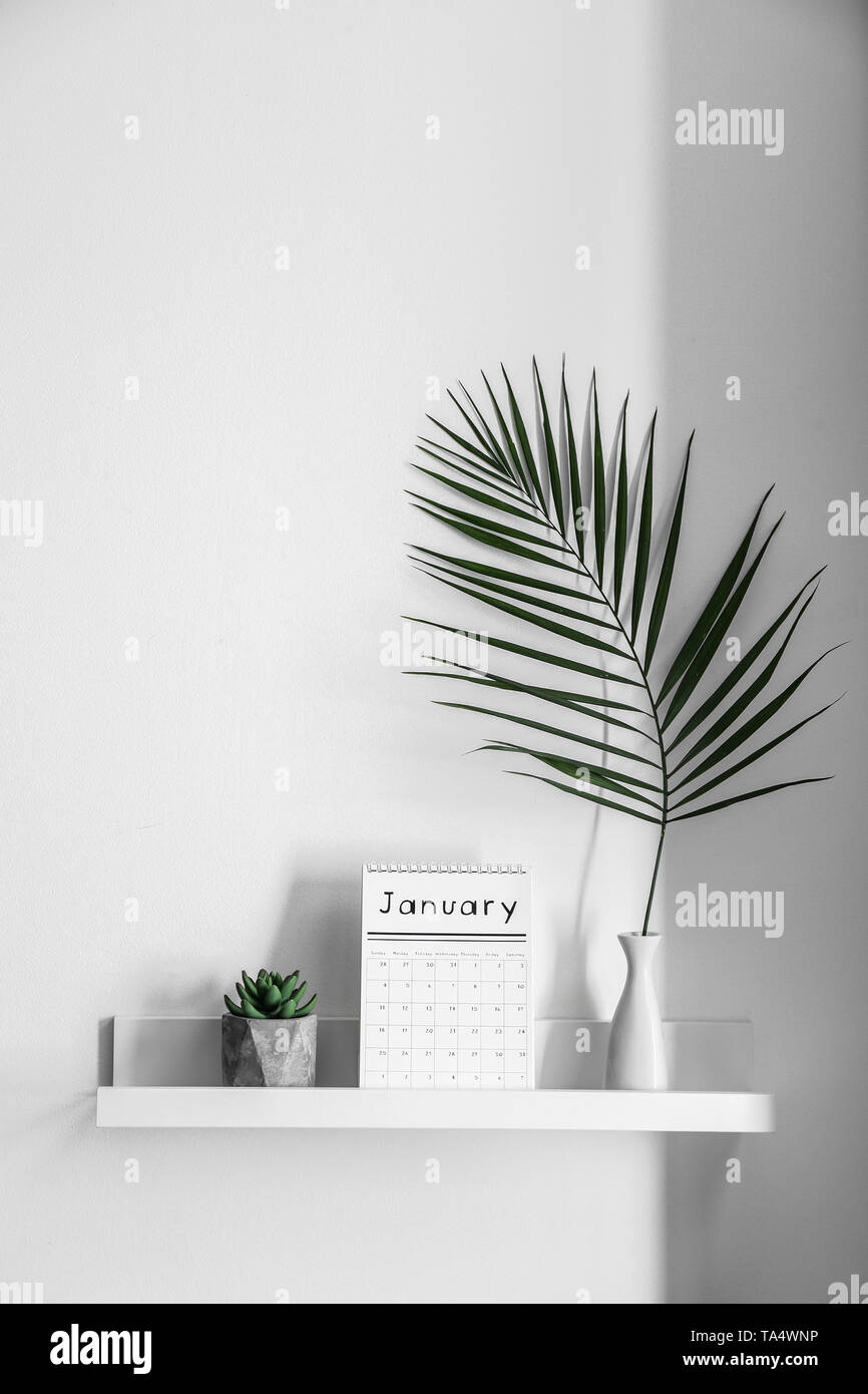 Flip calendar and vase with tropical leaf on shelf Stock Photo - Alamy