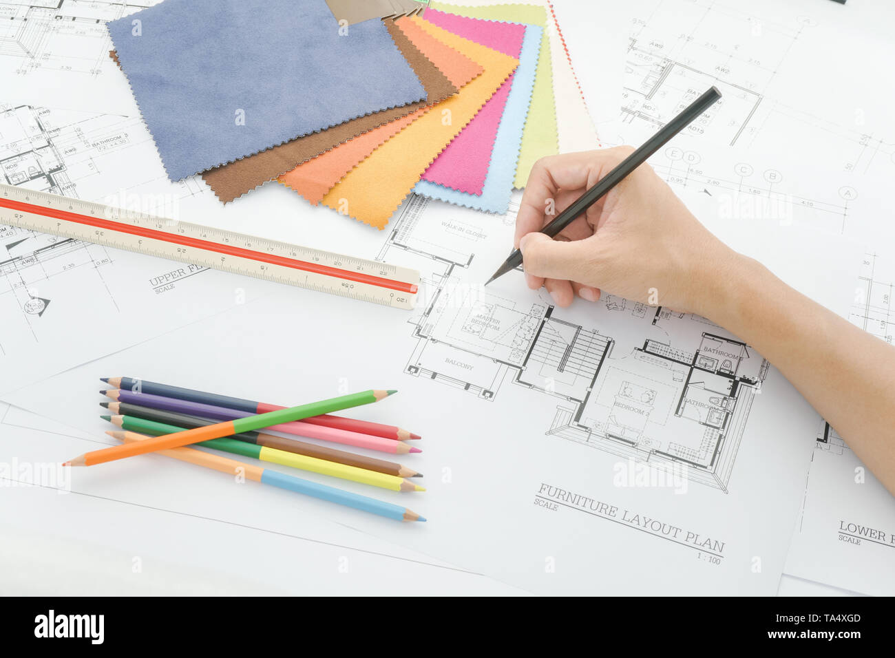 Hand writing on architectural plan with fabric sample on interior ...