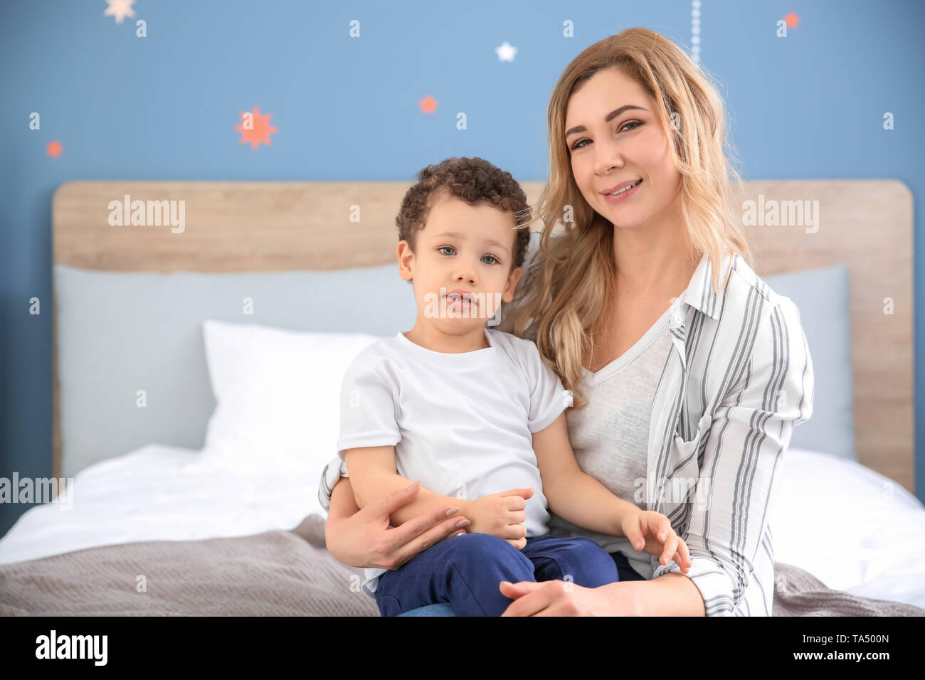 Young mother with cute little son sitting on bed at home Stock Photo - Alamy