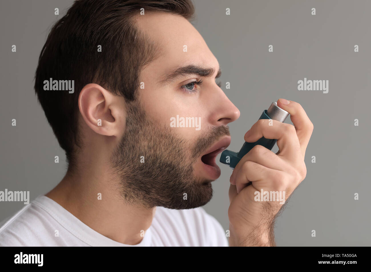 Young man with inhaler having asthma attack on grey background Stock ...
