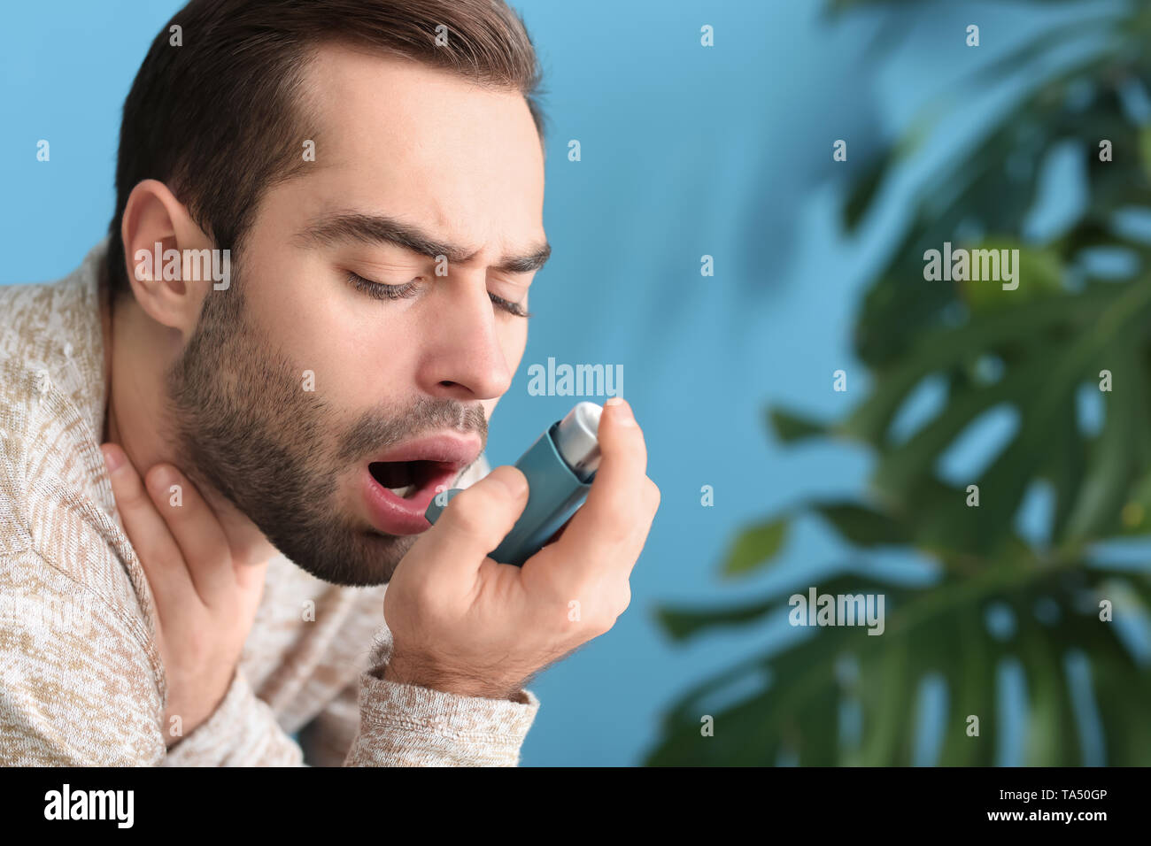 Young man with inhaler having asthma attack at home Stock Photo - Alamy