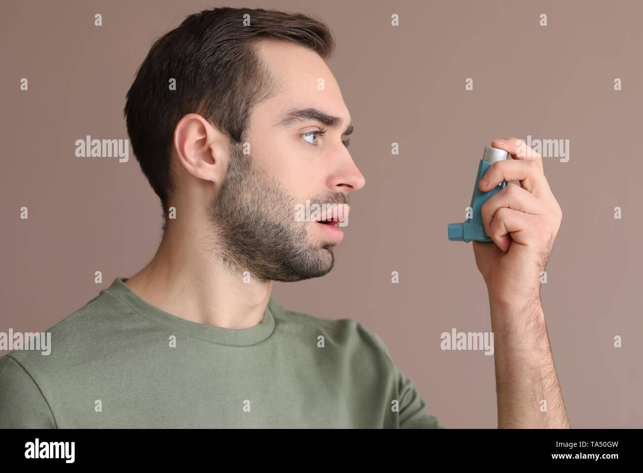 Young man with inhaler on color background Stock Photo - Alamy