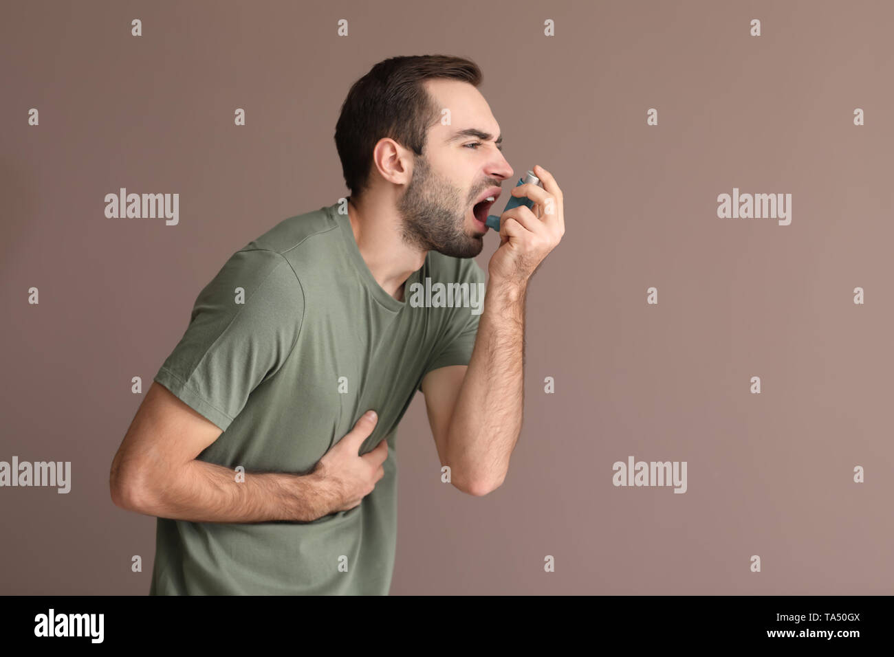 Young man with inhaler having asthma attack on color background Stock ...