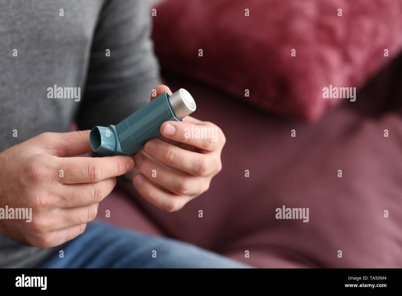 Young man with inhaler at home, closeup Stock Photo - Alamy