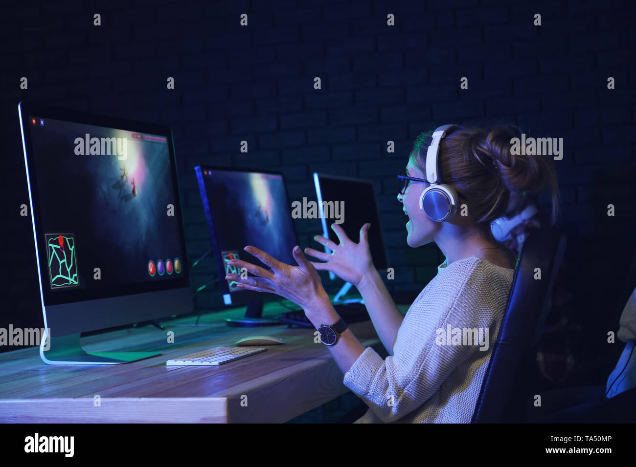 Emotional young woman playing computer game in club Stock Photo - Alamy