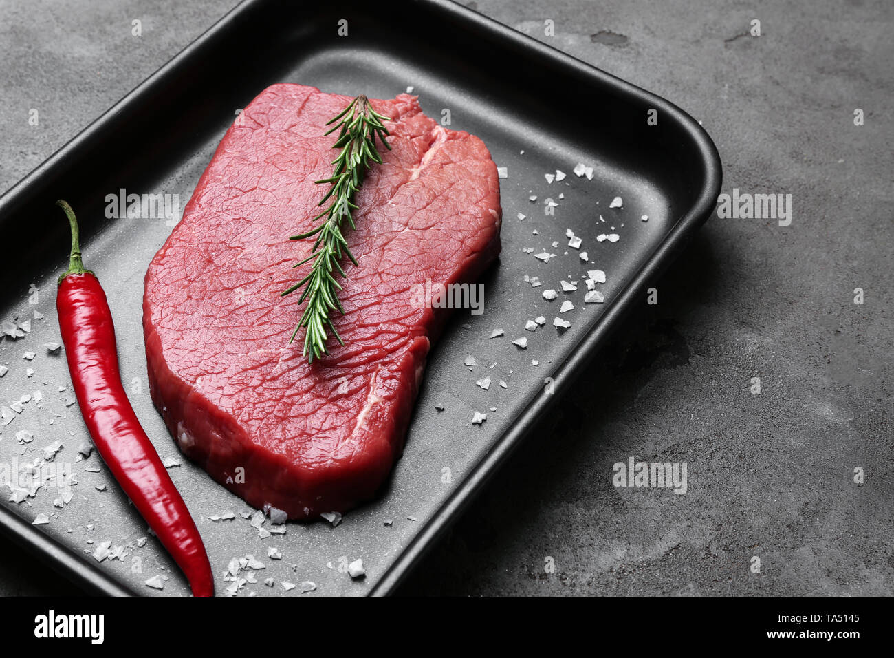 Container with tasty raw meat on grunge background Stock Photo - Alamy