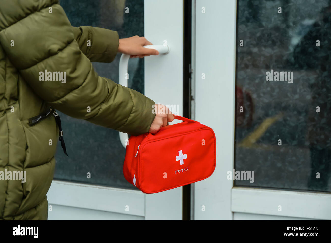 Woman with first aid kit opening door Stock Photo - Alamy