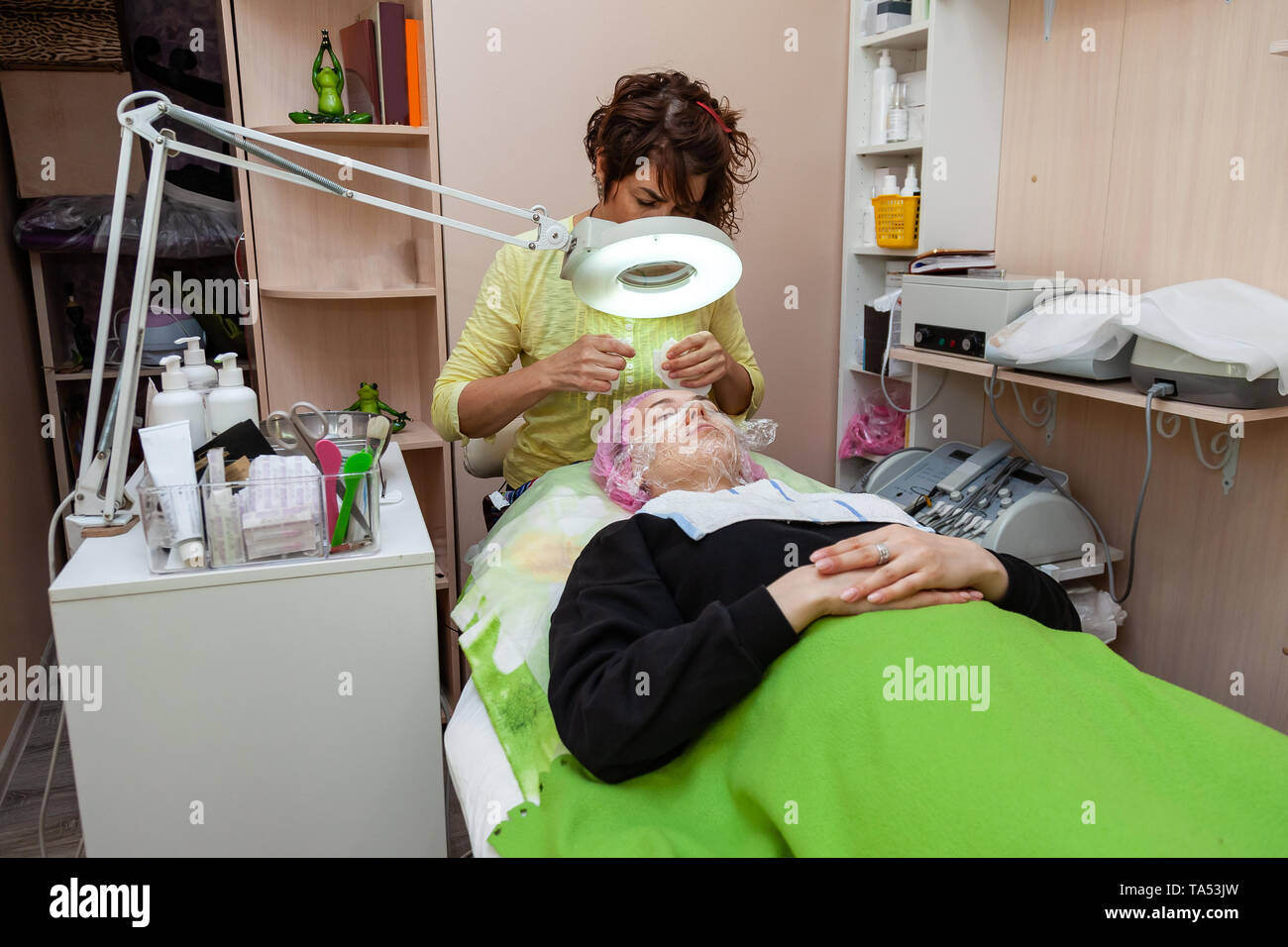 A young girl is lying on a couch during cosmetic procedures with a mask ...