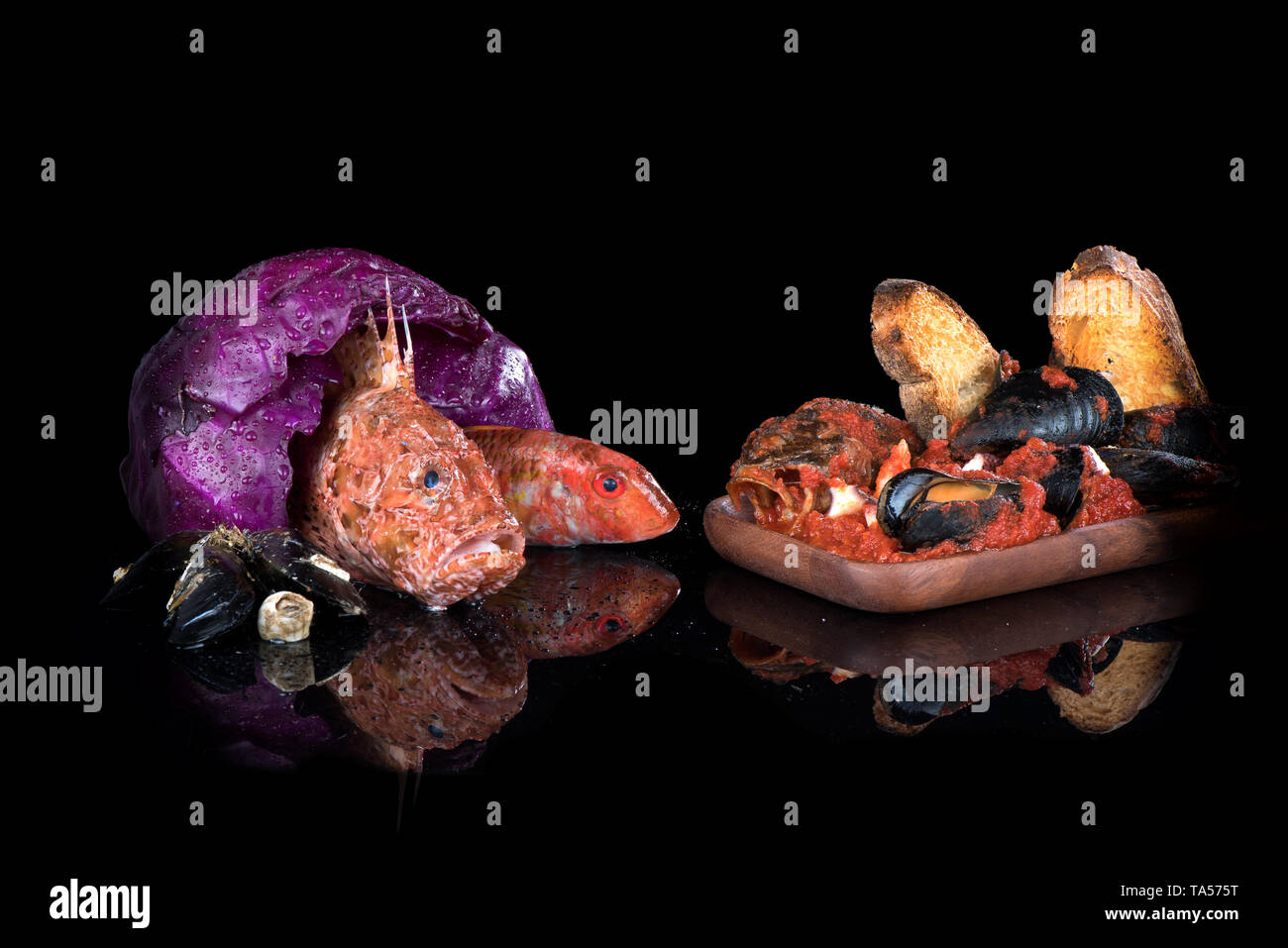 Fish soup, raw fish, scorpion fish, red mullet, crabs on a black ...