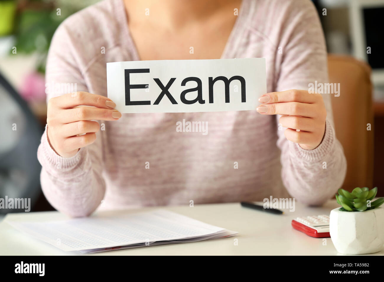 Girl holding paper with word EXAM in classroom Stock Photo - Alamy