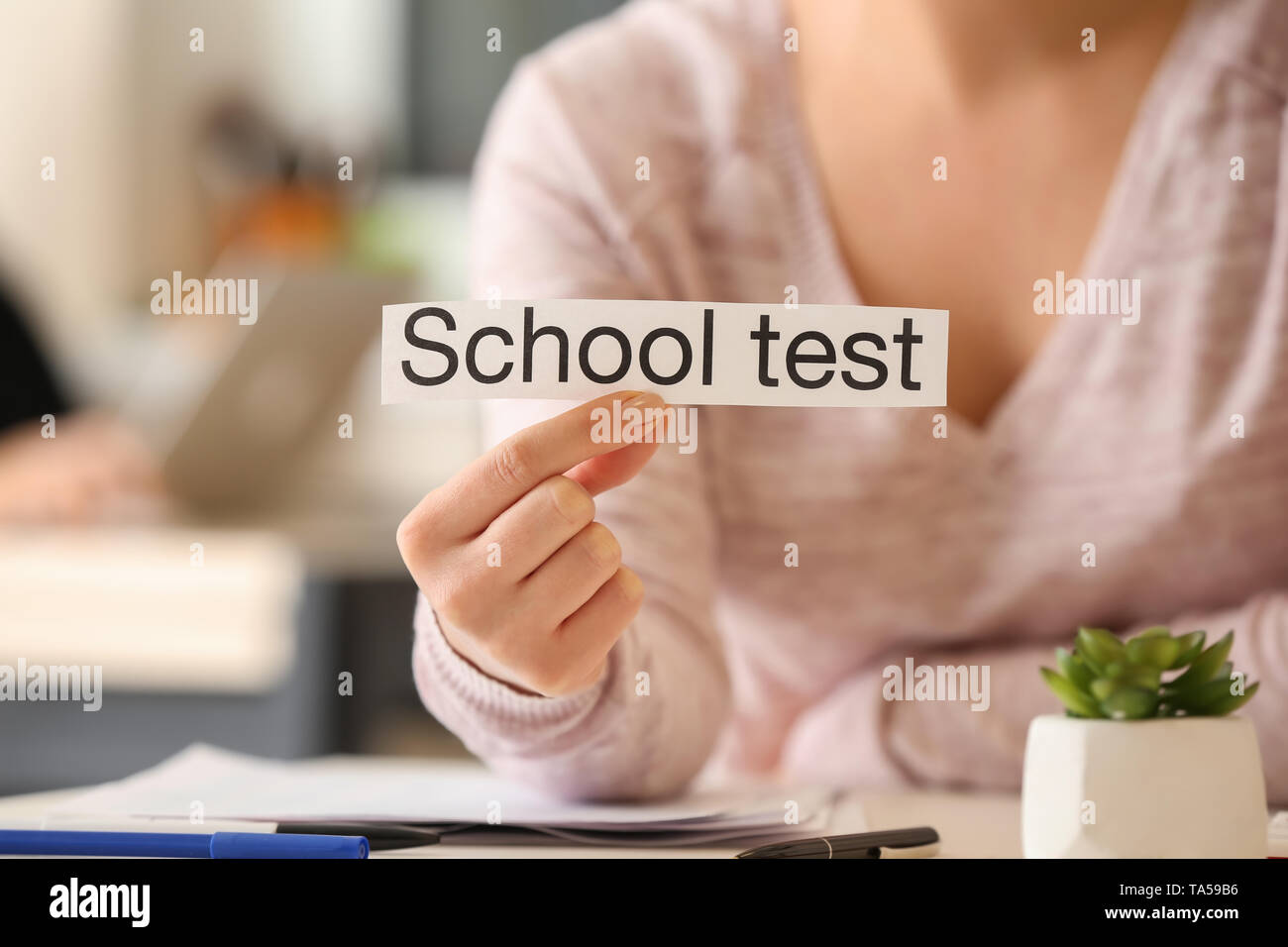 Girl holding paper with text SCHOOL TEST in classroom Stock Photo - Alamy