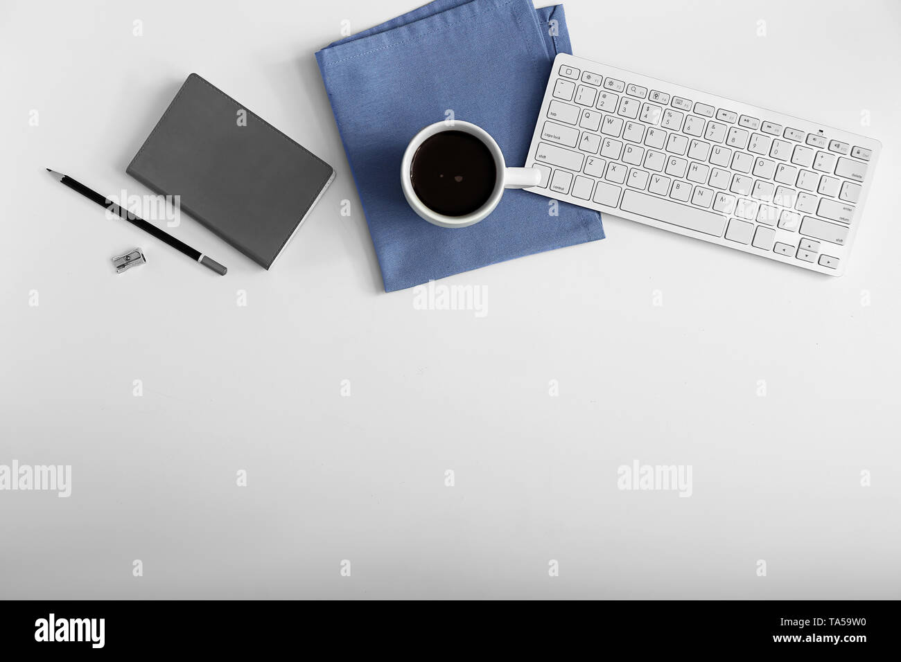 Computer keyboard with cup of coffee and stationery on white background ...