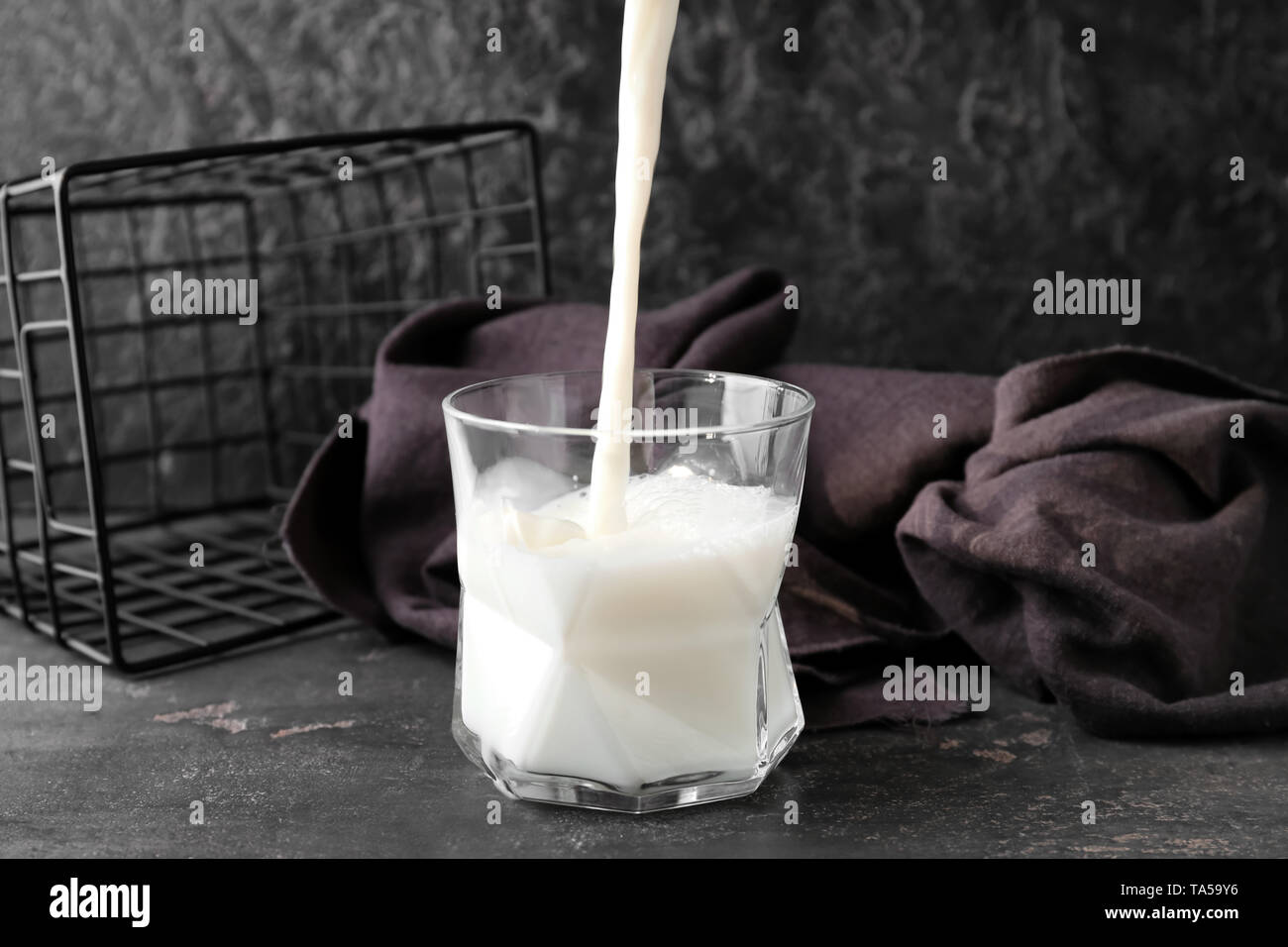 Pouring of milk into glass on table Stock Photo - Alamy
