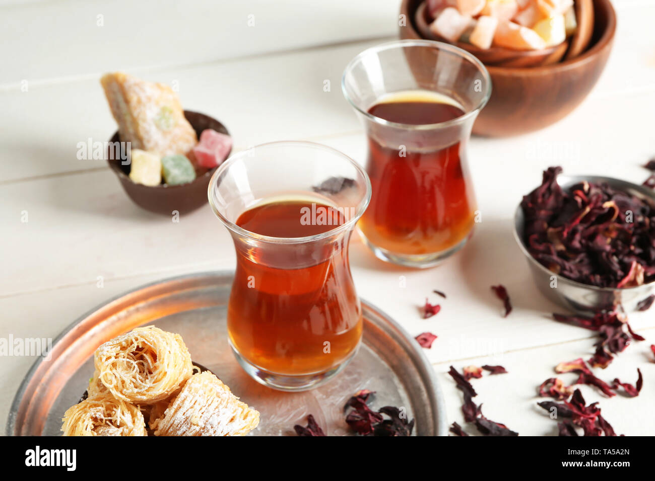 Turkish tea in traditional glasses with East sweets on white table ...